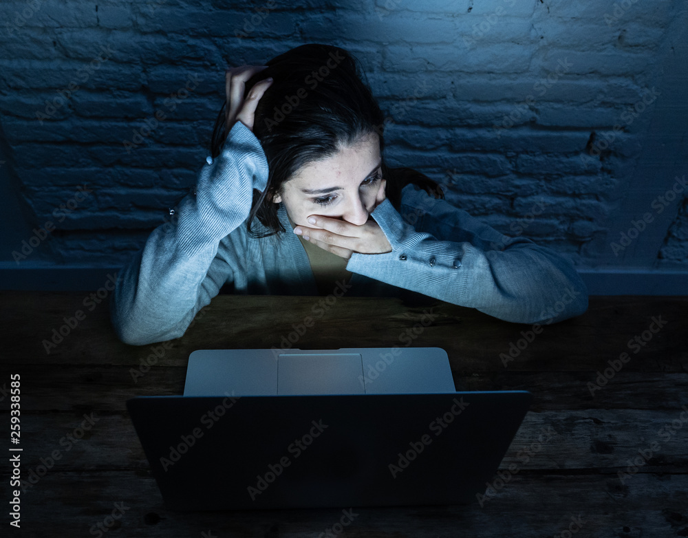 Scared woman on laptop in the dark feeling fear suffering online ...