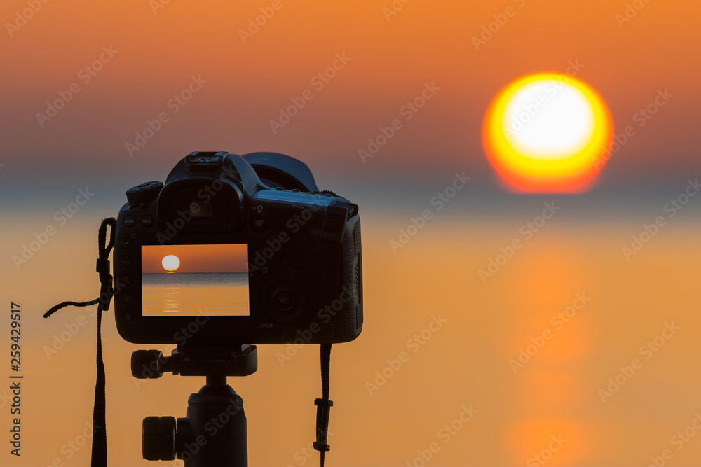 Eine Kamera fotografiert den Sonnenaufgang und im Display ist das ...
