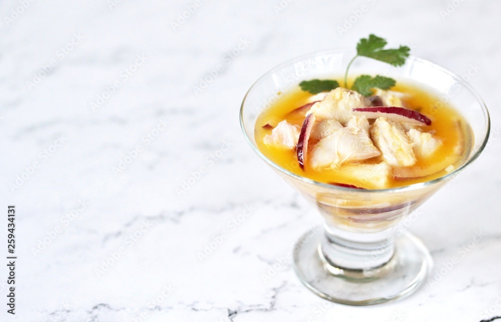 white fish ceviche in orange juice, served in a glass ice-cream bowl ...
