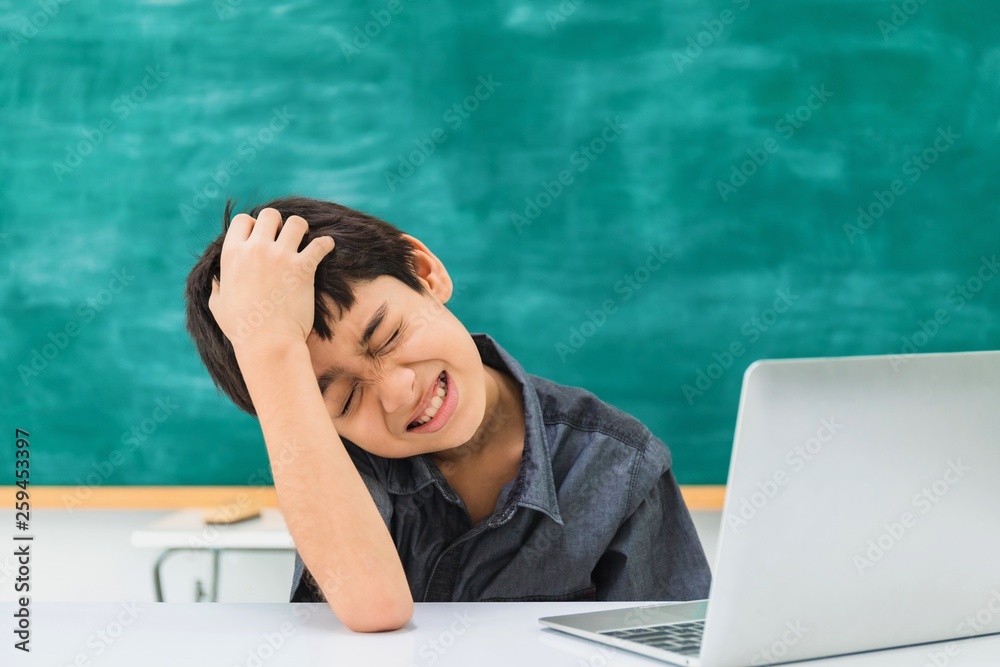 Asian confused school boy using laptop on black board background with ...