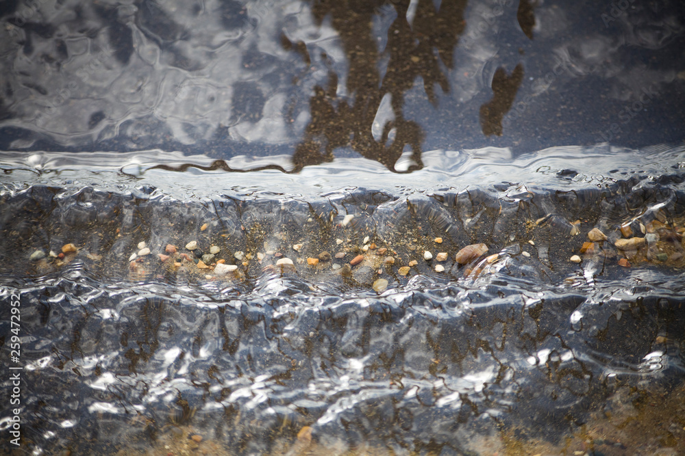 Background water. Asphalt and sand. Stream of water over the asphalt ...