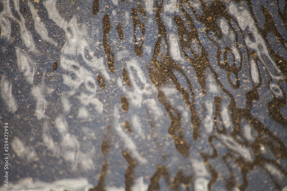 Background water. Asphalt and sand. Stream of water over the asphalt ...