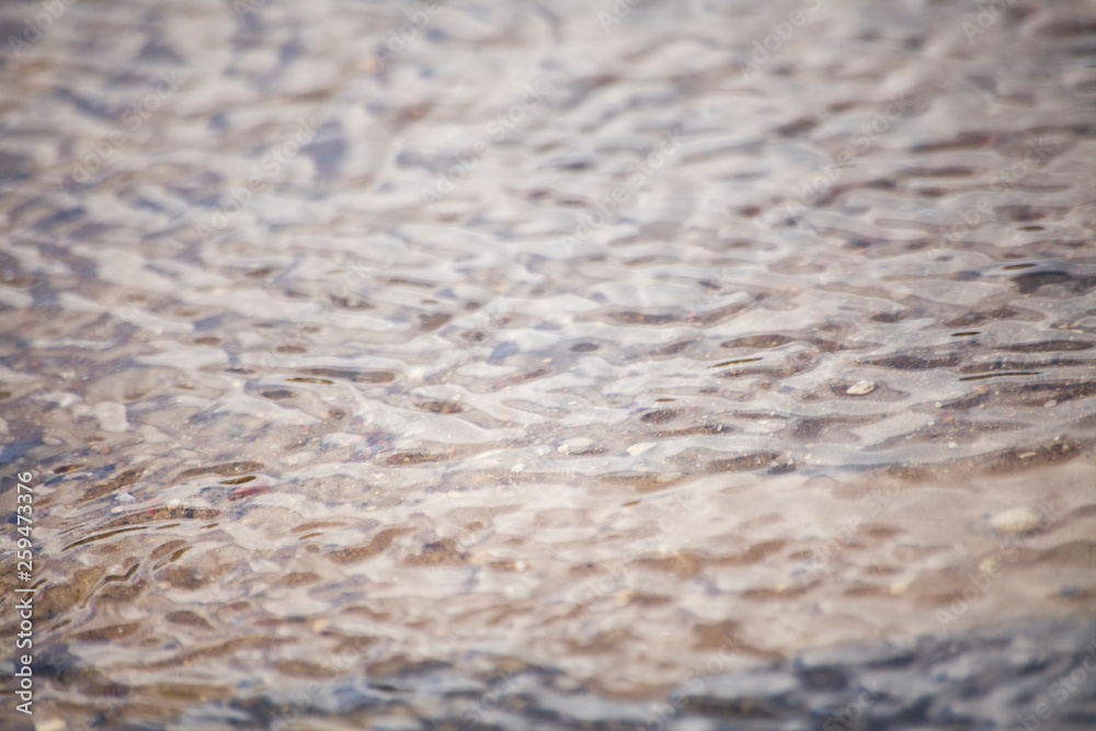 Background water. Asphalt and sand. Stream of water over the asphalt ...