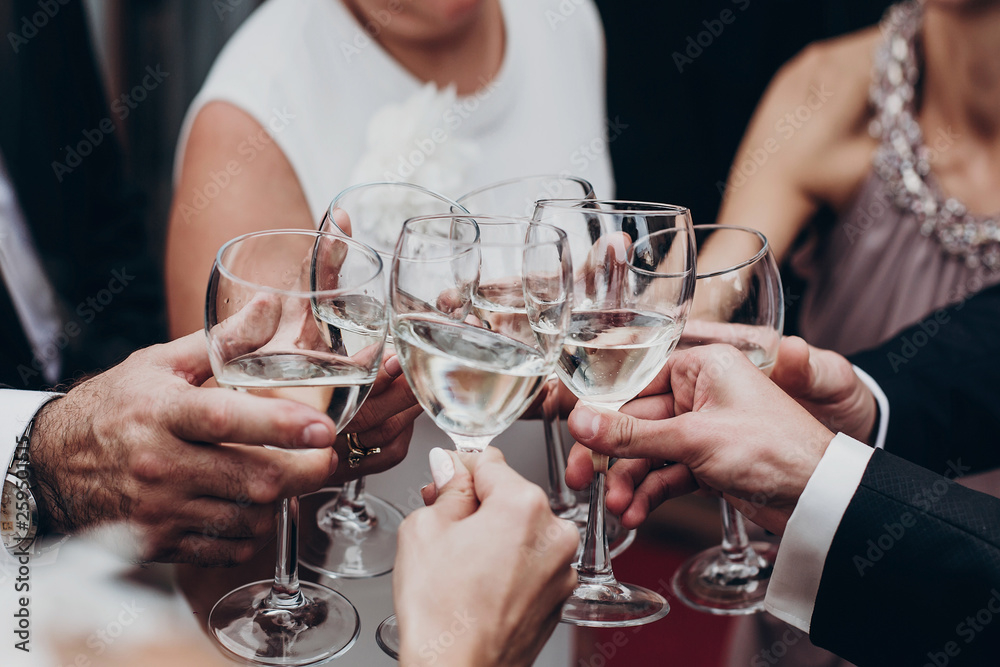 people toasting with champagne and wine glasses in hands clinking at ...