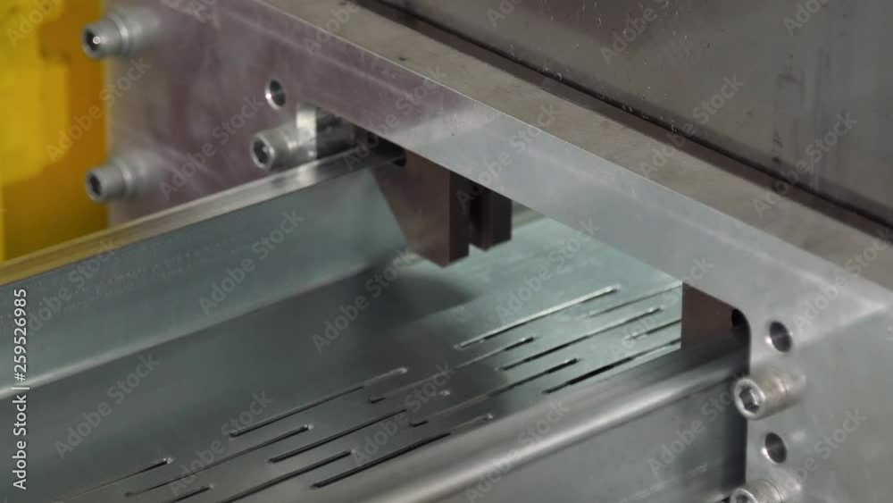 Closeup of a length of steel of cable tray being stamped & cut on a ...