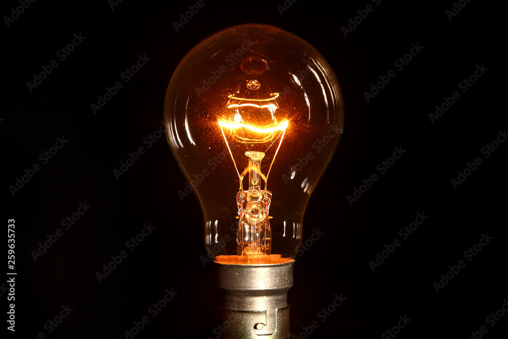 Clear glass electric lightbulb dimmed to enable it's tungsten filament ...