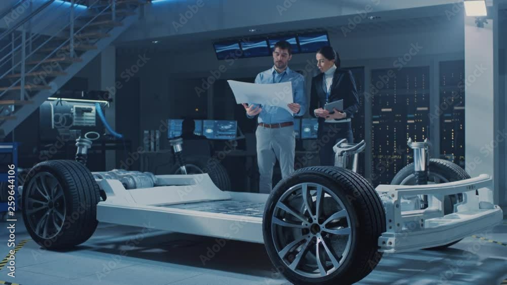 Auto Industry Design Facility: Male Chief Engineer Shows Car Blueprints ...