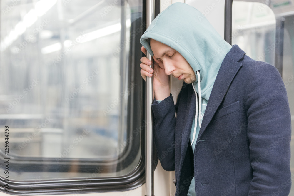 A tired man after work goes home on the subway train. Young exhausted ...