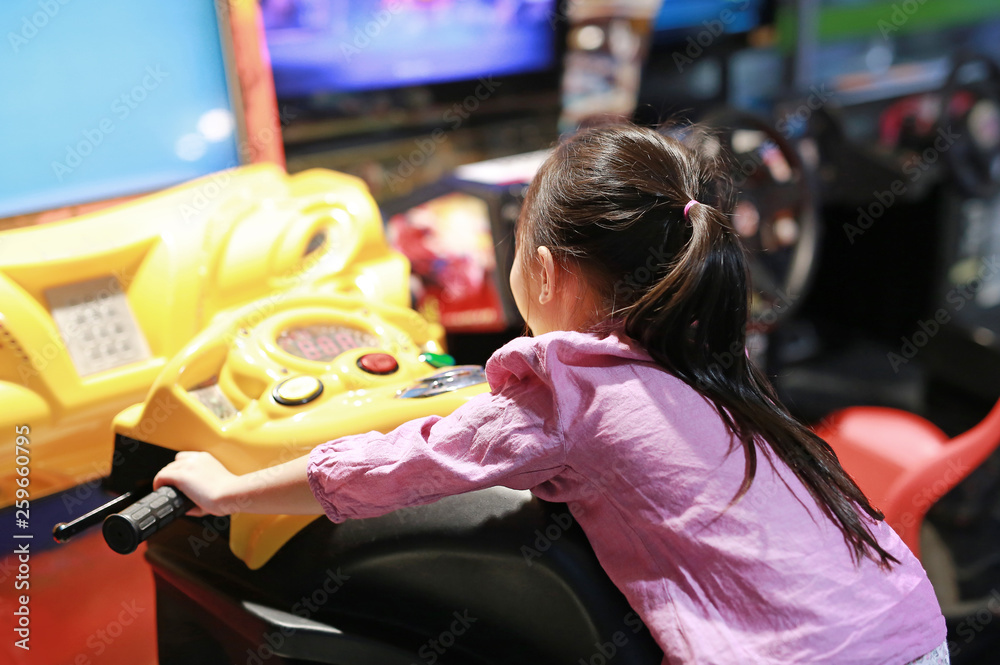 little Asian kid girl playing arcade video game. Motorcycle Racing ...