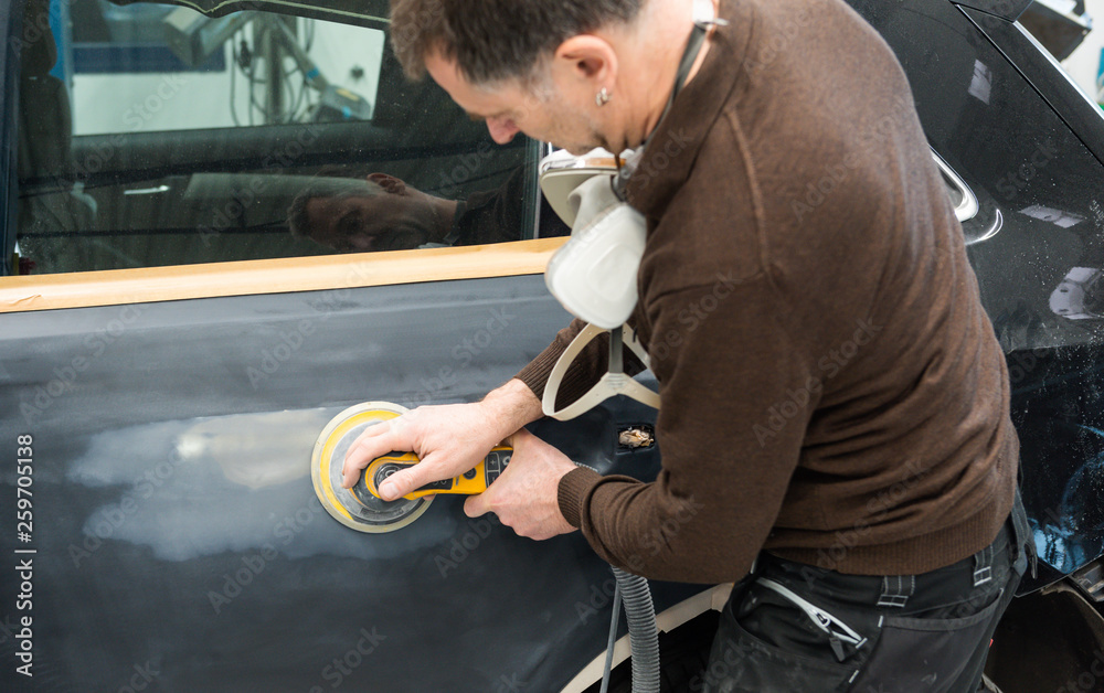 Professioneller Autolackierer schleift ein Autoteil mit der ...