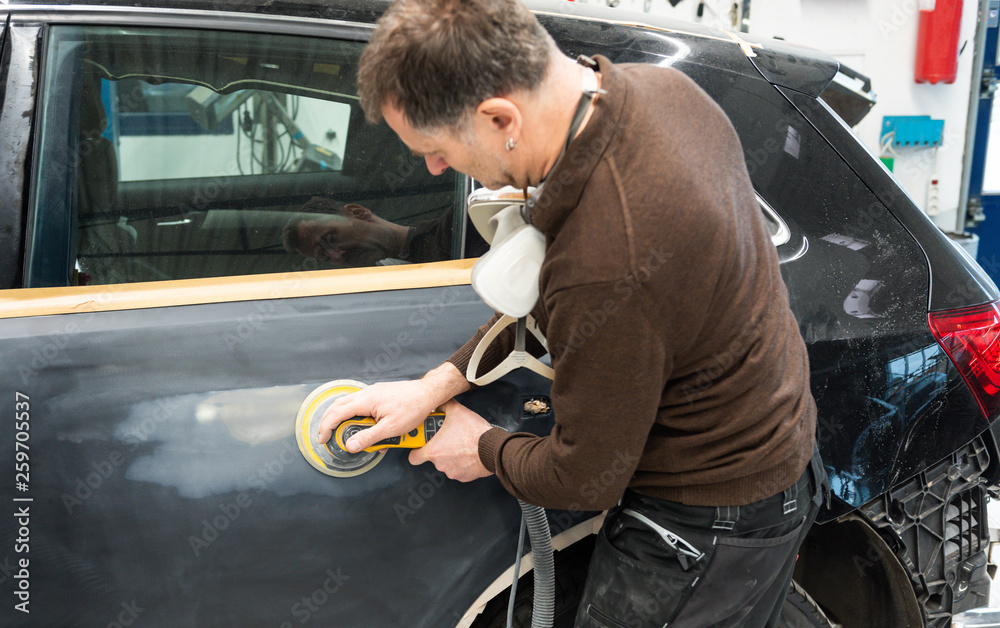 Professioneller Autolackierer schleift ein Autoteil mit der ...