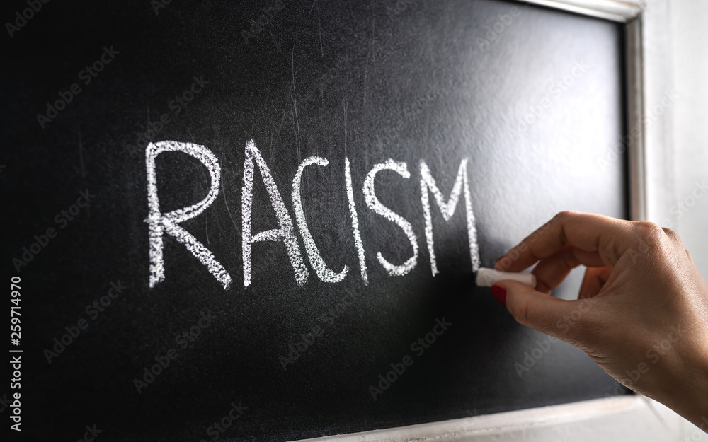 Hand writing the word racism on blackboard. Stop hate. Against ...