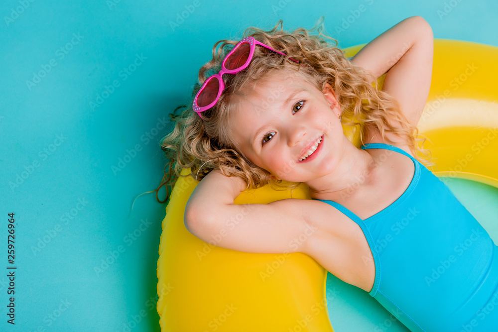 Cute girl in swimsuit holding swimming circle. Isolated on blue ...