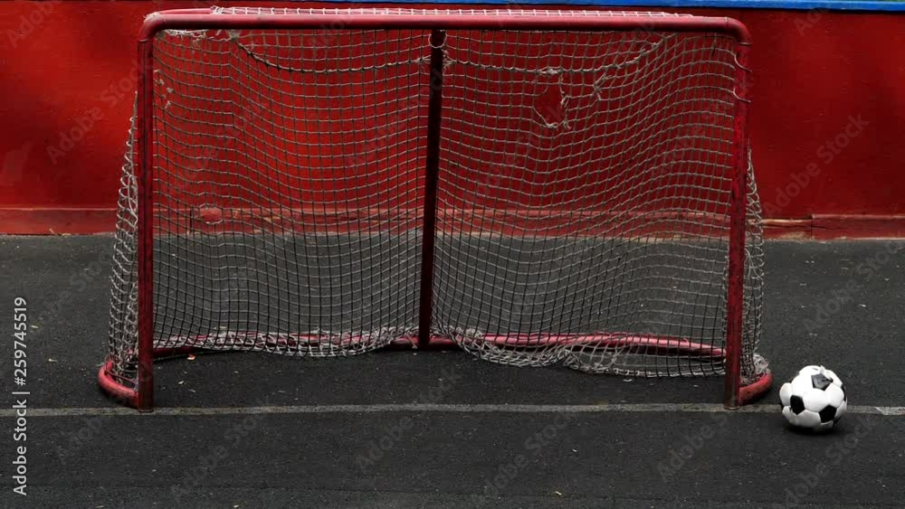 Broken soccer ball roll out of empty goal gate, bad shot, slow motion ...