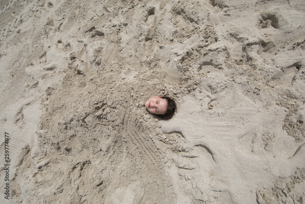 little girl buried in the sand on the beach Stock Photo | Adobe Stock