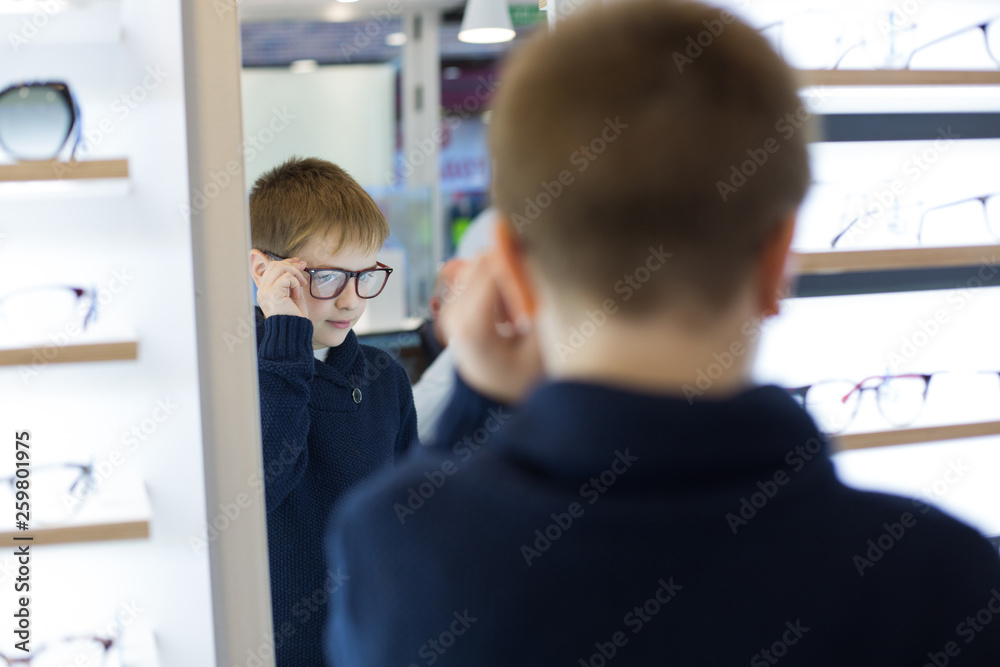 Cute young boy trying on glasses in an eyewear store Stock Photo ...