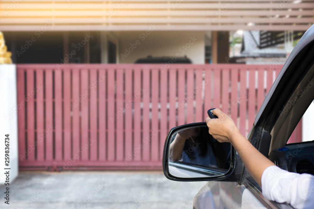 Woman in car, hand using remote control to open auto wooden door with ...