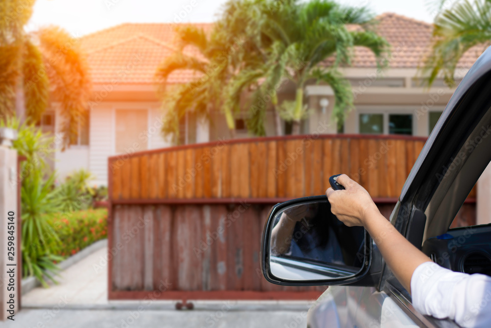 Woman in car, hand using remote control to open auto wooden door with ...