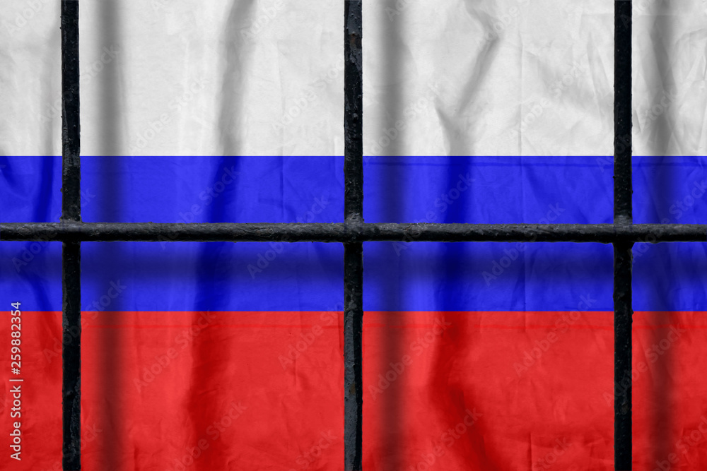 Russian flag behind black metal bars of a prison grate with shadows ...