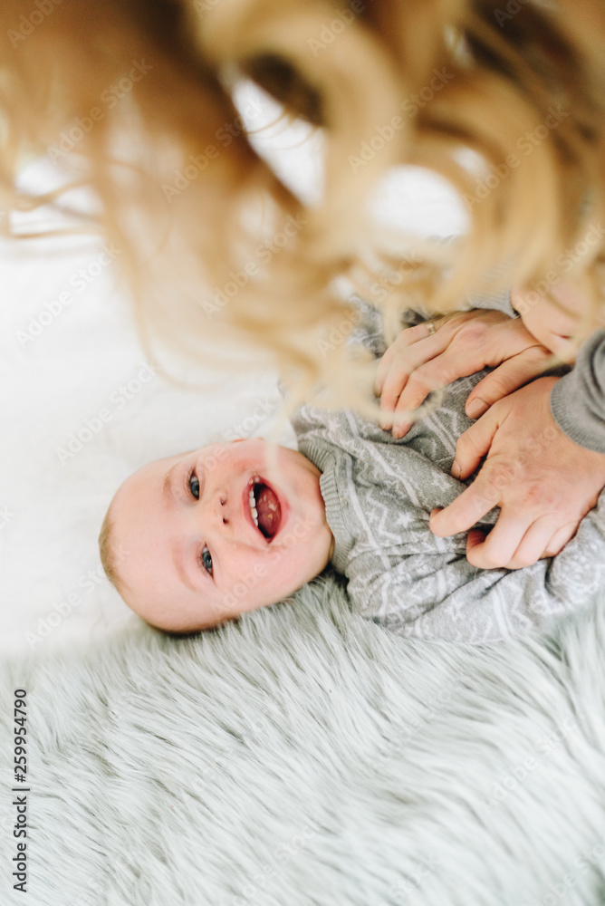Cute little baby boy is tickled by his mother. Happy and smiling child ...