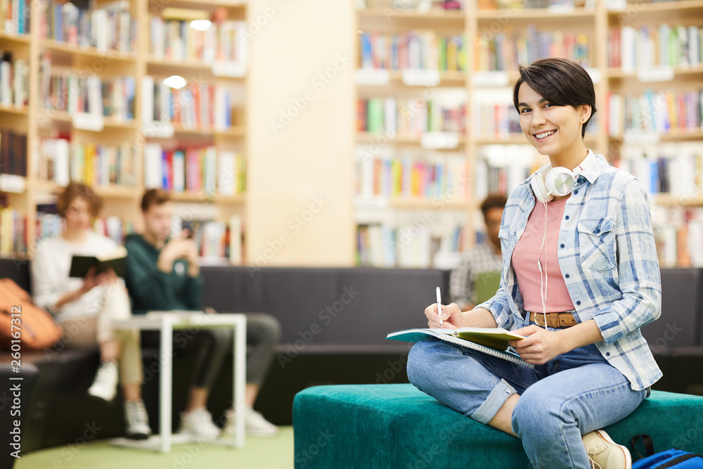 Positive confident pretty girl with white headphones on neck sitting on ...