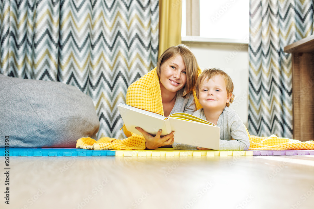 Happy and beautiful mother and child, family together reading a book ...