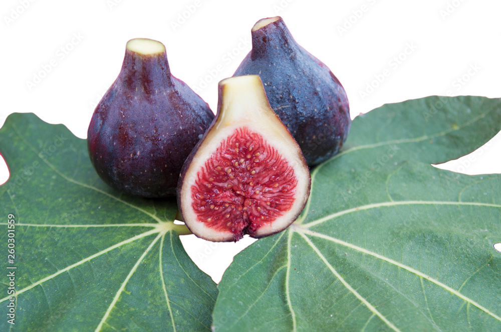three ripe figs on a green leaf from the Fig tree, one Fig is cut in ...