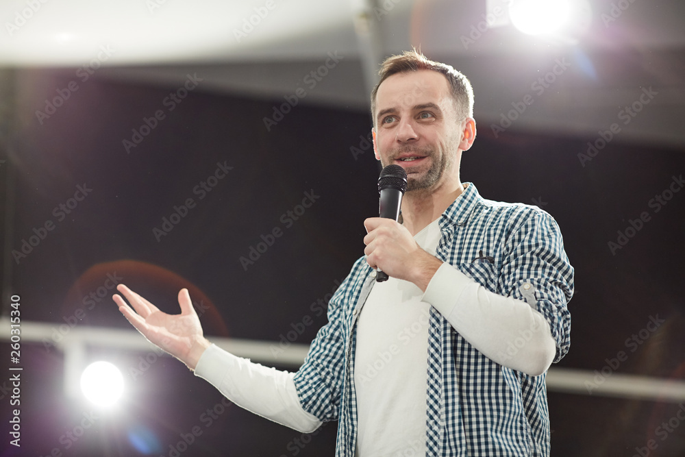 Waist up portrait of mature man giving speech standing on stage in ...