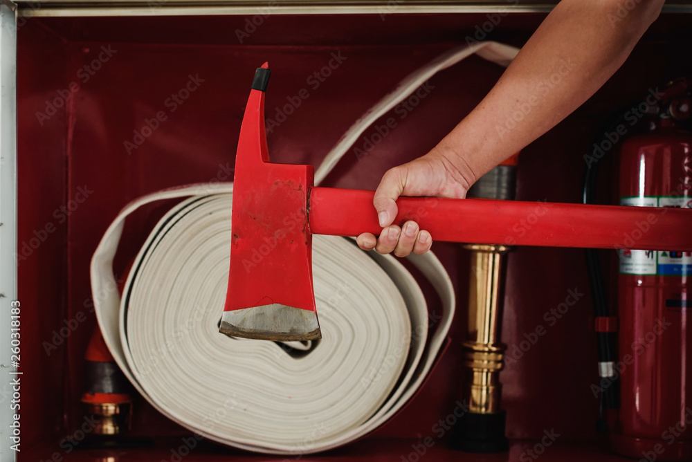 Rescue firefighter hand holding ax and firefighting equipment in red ...