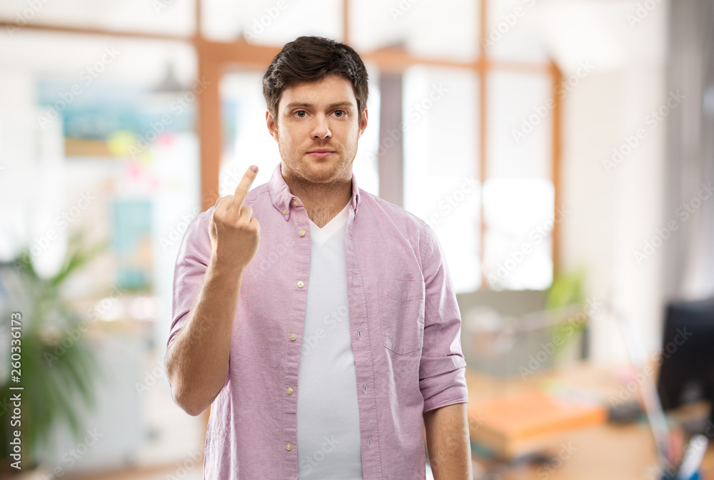 people concept - young man showing middle finger over office room ...