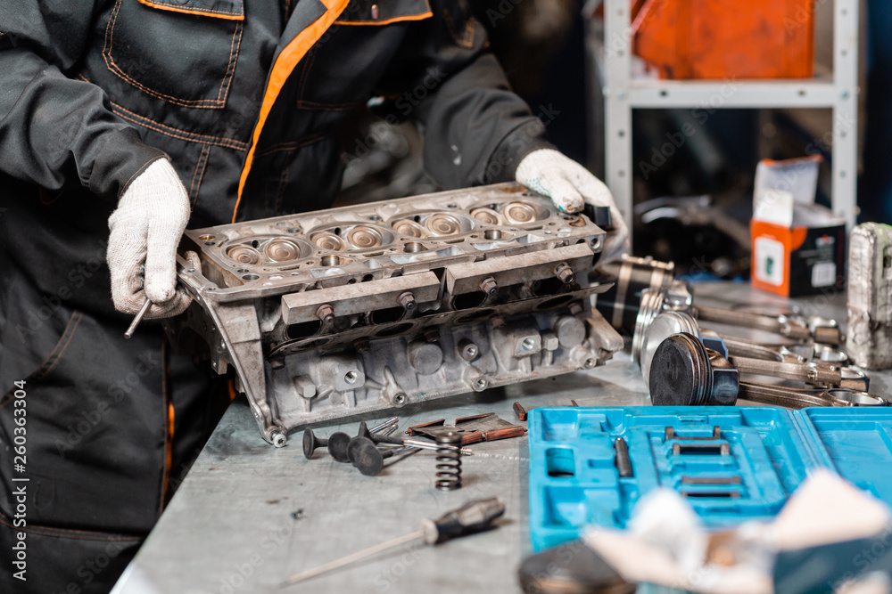 Mechanic disassembling the engine, overhaul.. Engine on a repair stand ...