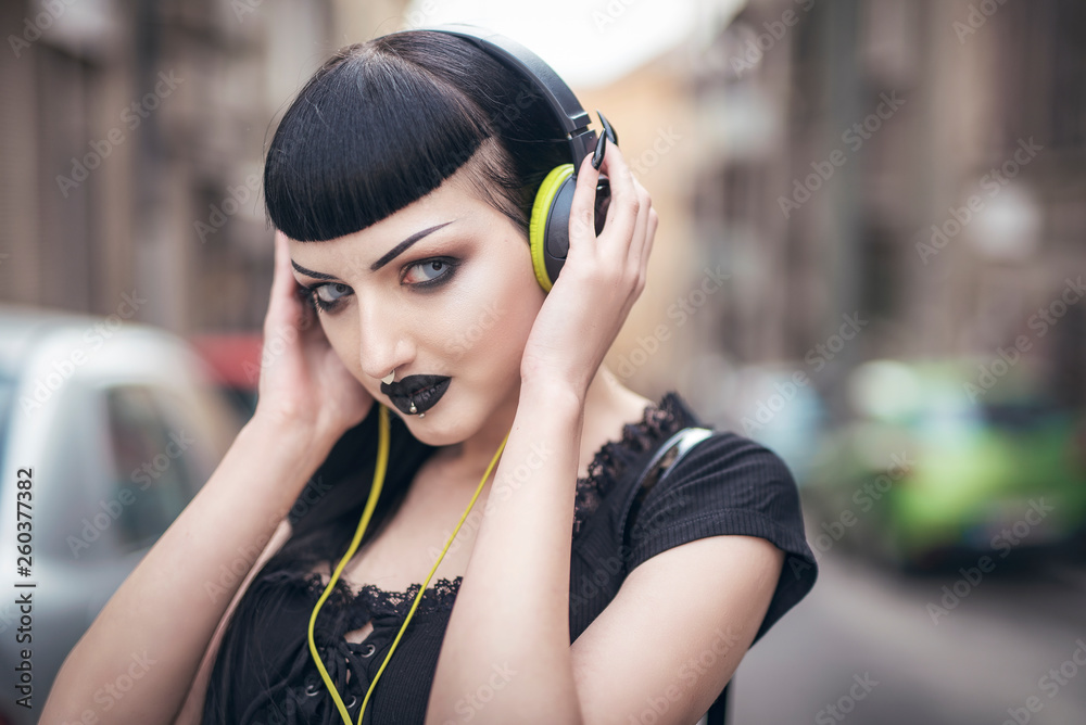 Urban goth girl listening to her favourite music over her big ...