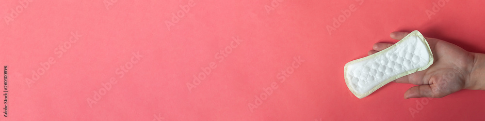 woman's hand holding a sanitary pad on the pink background. A large ...