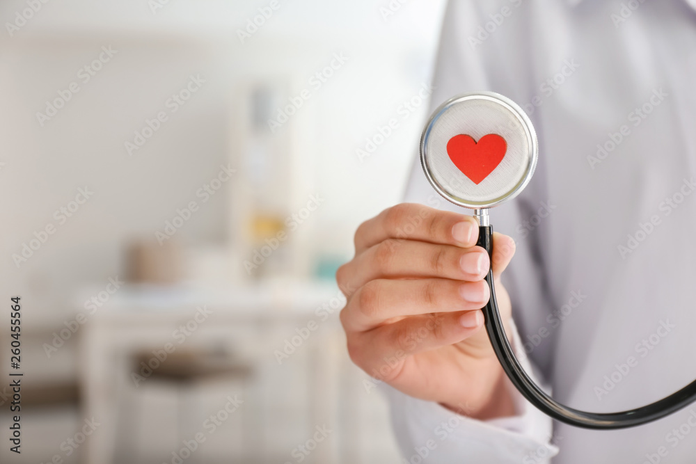 Cardiologist holding stethoscope with red heart in clinic, closeup ...