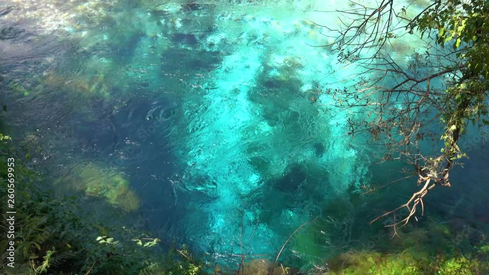 Fresh turquoise colored water bubbles out of the well and fills up the ...