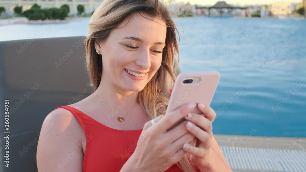 Portrait smiling bikini woman using mobile phone on chaise long. Summer ...