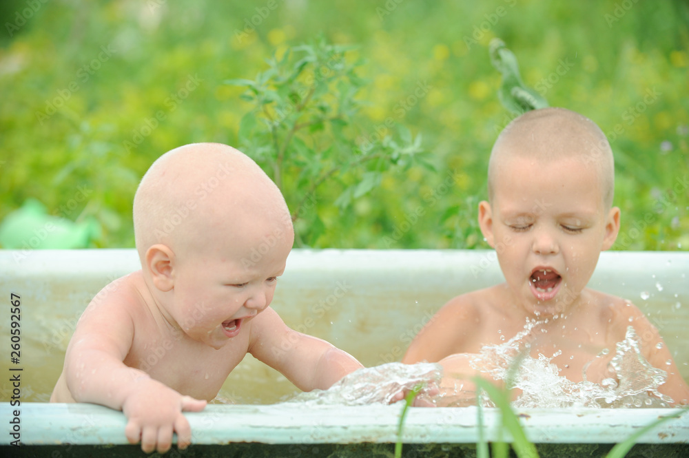 Children bathe in pool made from old bathroom tank and placed in garden ...
