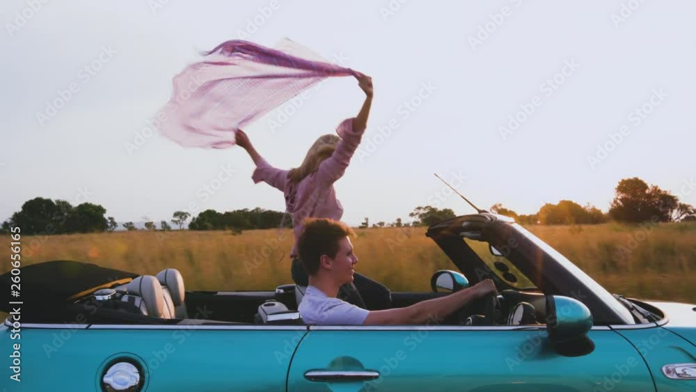 4K backlit side view of a happy young couple out in the country driving ...