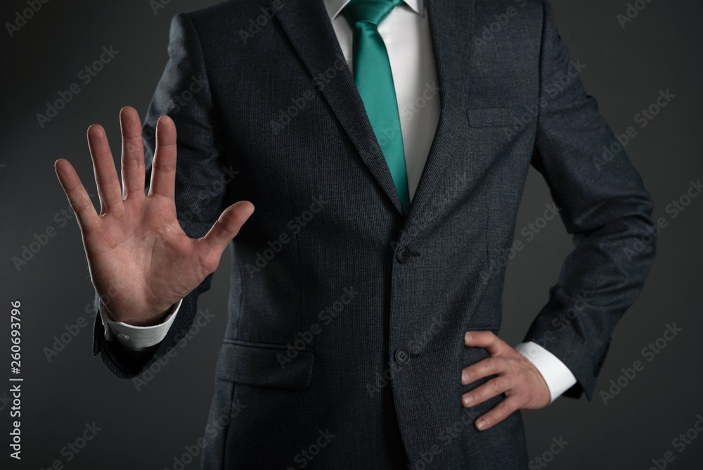 Business man is showing a stop gesture by his hand on a gray background ...