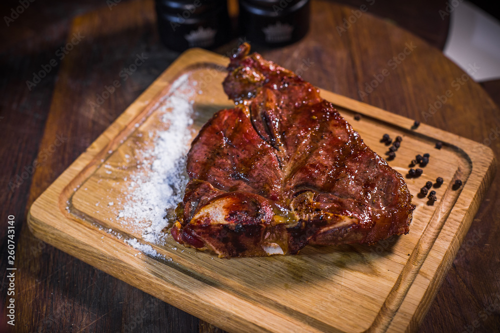 Grilled pork rib chop steak in a clay plate with oil, mustard, salt and ...