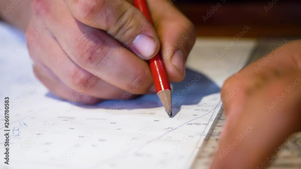 Close up of the Captain's hands using a pencil and protractor on a ...