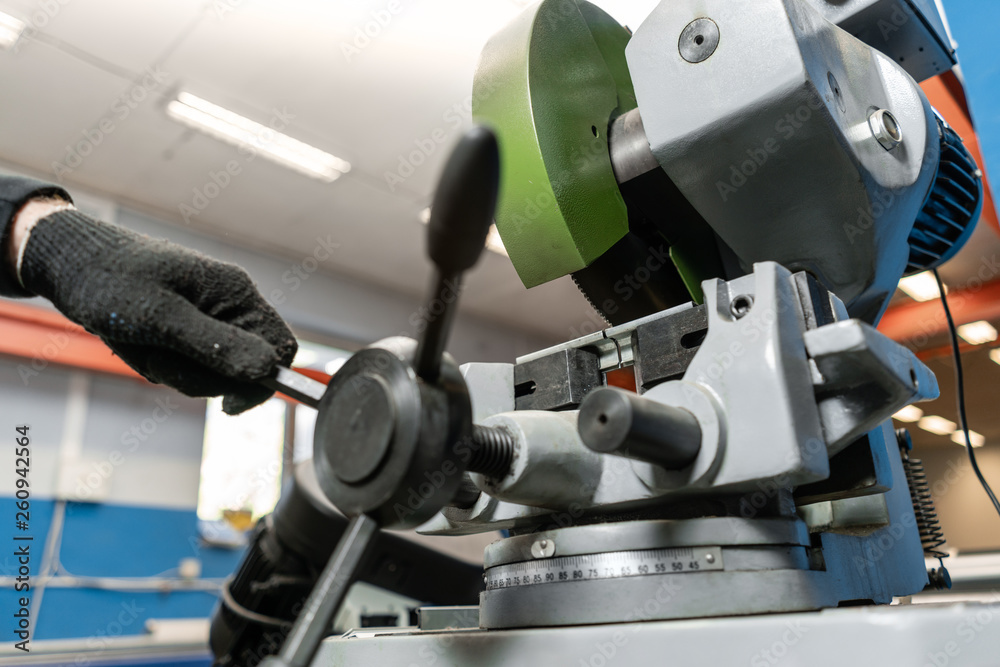 worker cuts a piece of material with a circular saw machine. Industrial ...