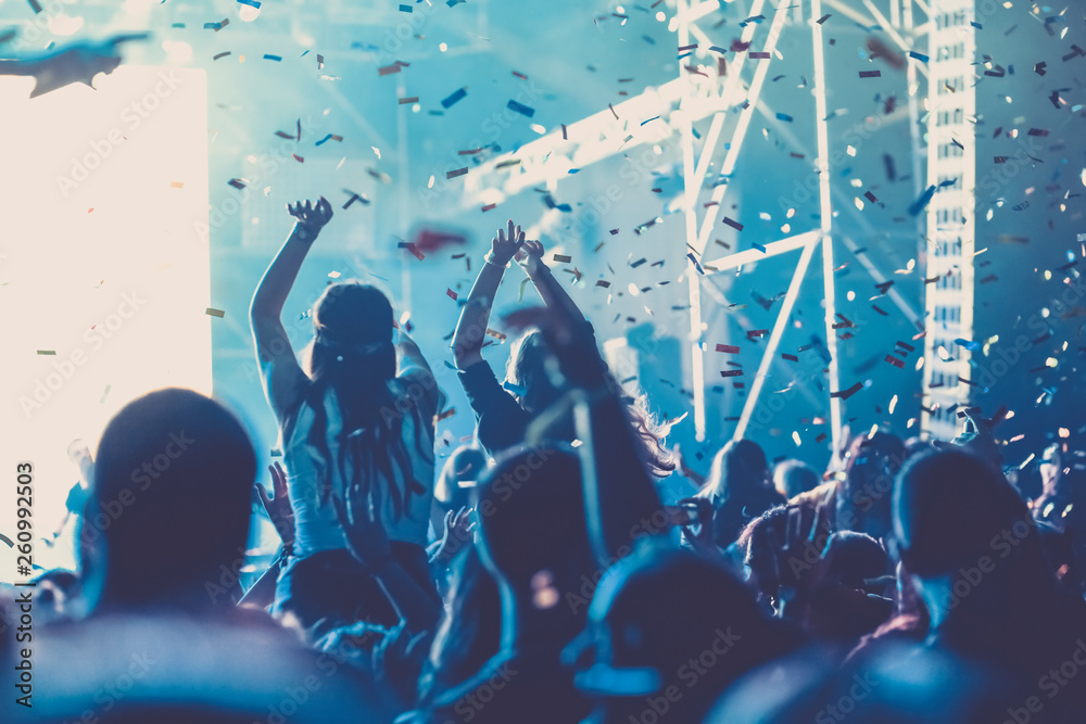 cheering crowd with raised hands and falling confetti at concert ...
