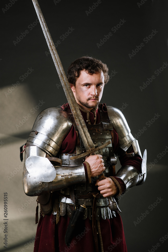 Medieval man knight in armor and weapon on dark background. Portrait of ...