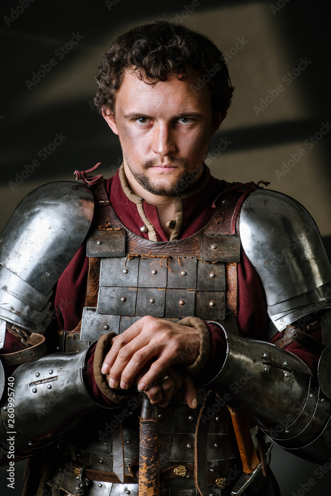 Medieval man knight in armor and weapon on dark background. Portrait of ...