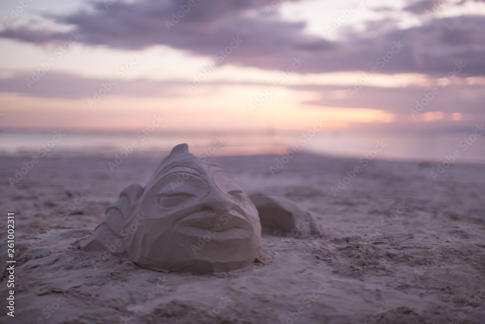 man has modeling an artistic fish sculpture out of sand at a white ...