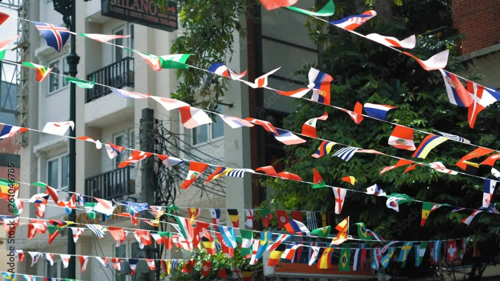 Flags of many countries hang on ropes in the air at the city background ...