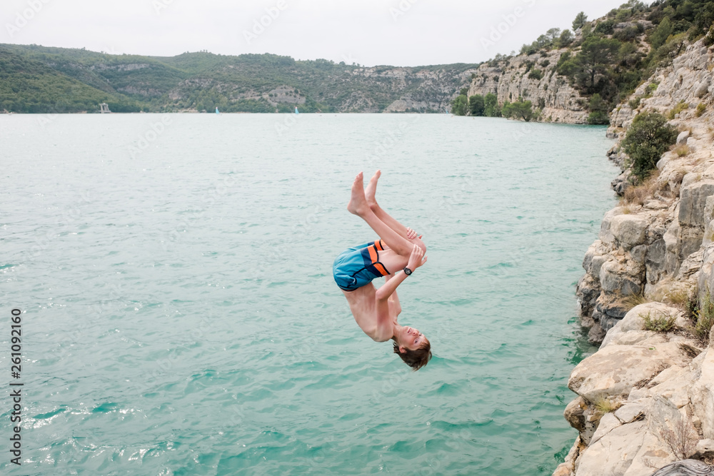teen boy doing a flip off a cliff in a lake in Provence Stock Photo ...