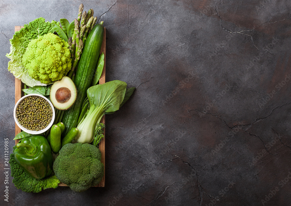 Assorted green toned raw organic vegetables in wooden box on dark ...