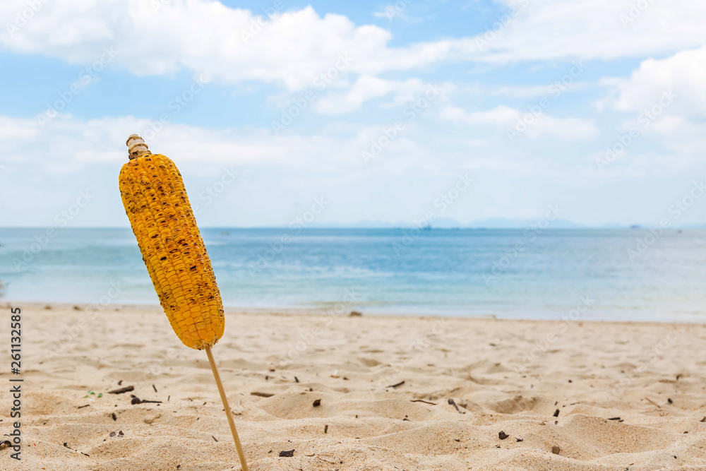 Ear of fried corn on a stick. Stuck in the sand on a tropical beach ...